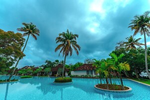 Um resort com uma piscina grande, palmeiras e edifícios em estilo tradicional.
