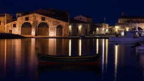 Um edifício à beira-mar com janelas em arco e um barco atracado na água.