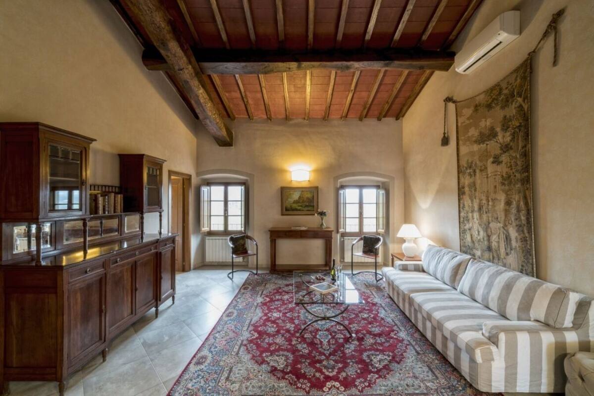 Uma sala de estar espaçosa com teto de madeira, um sofá listrado, um tapete com padrão vermelho e um armário de madeira.