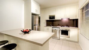 Uma cozinha moderna com uma ilha central, eletrodomésticos de aço inoxidável e armários brancos.