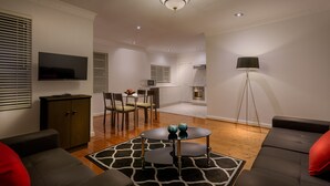 Uma sala de estar moderna com sofá, mesa de jantar e televisão na parede.