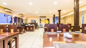 Uma ampla área de refeições com mesas e cadeiras altas, um espaço para café e um grande mural de girassol.