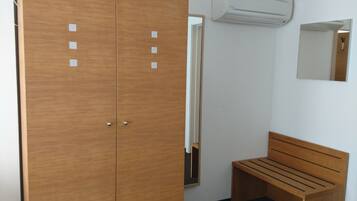 Quarto com guarda-roupa, um banquinho, um espelho e ar condicionado.