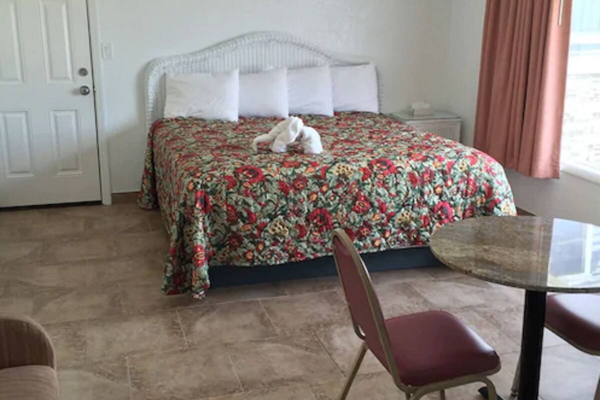 Quarto de hotel com cama, poltrona, mesa e porta.