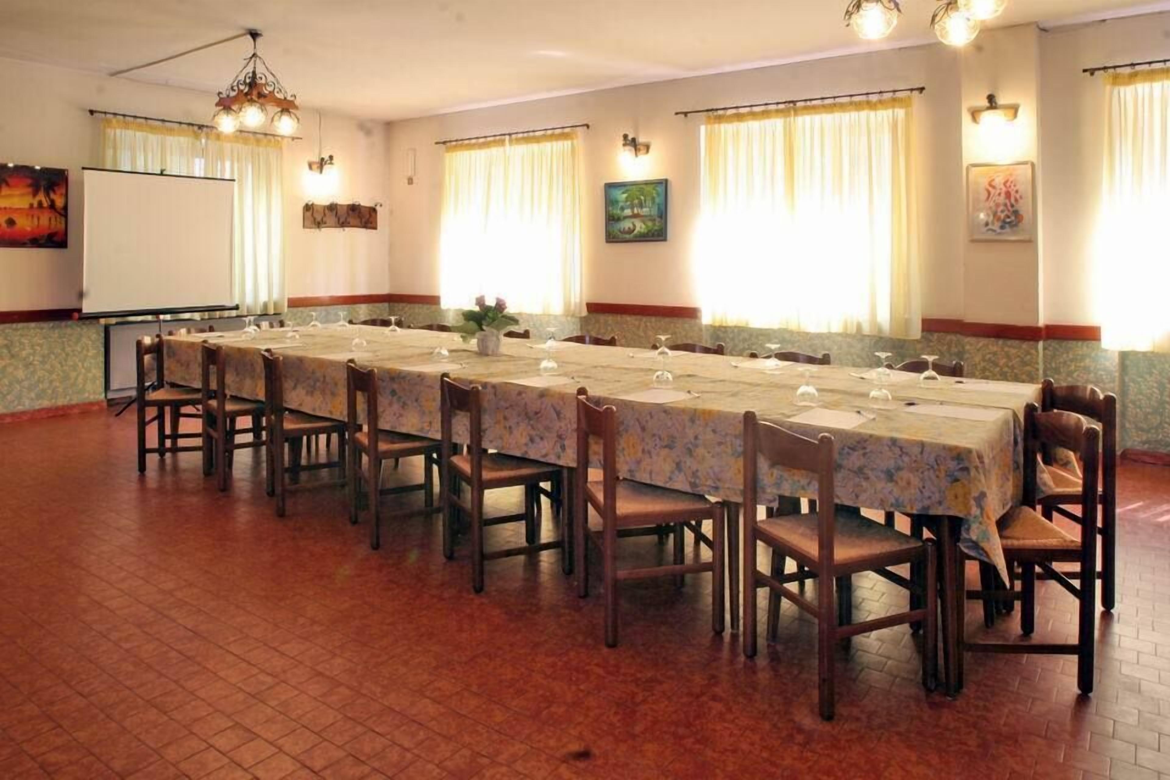 Uma sala de conferências com uma mesa comprida, cadeiras e um quadro branco.
