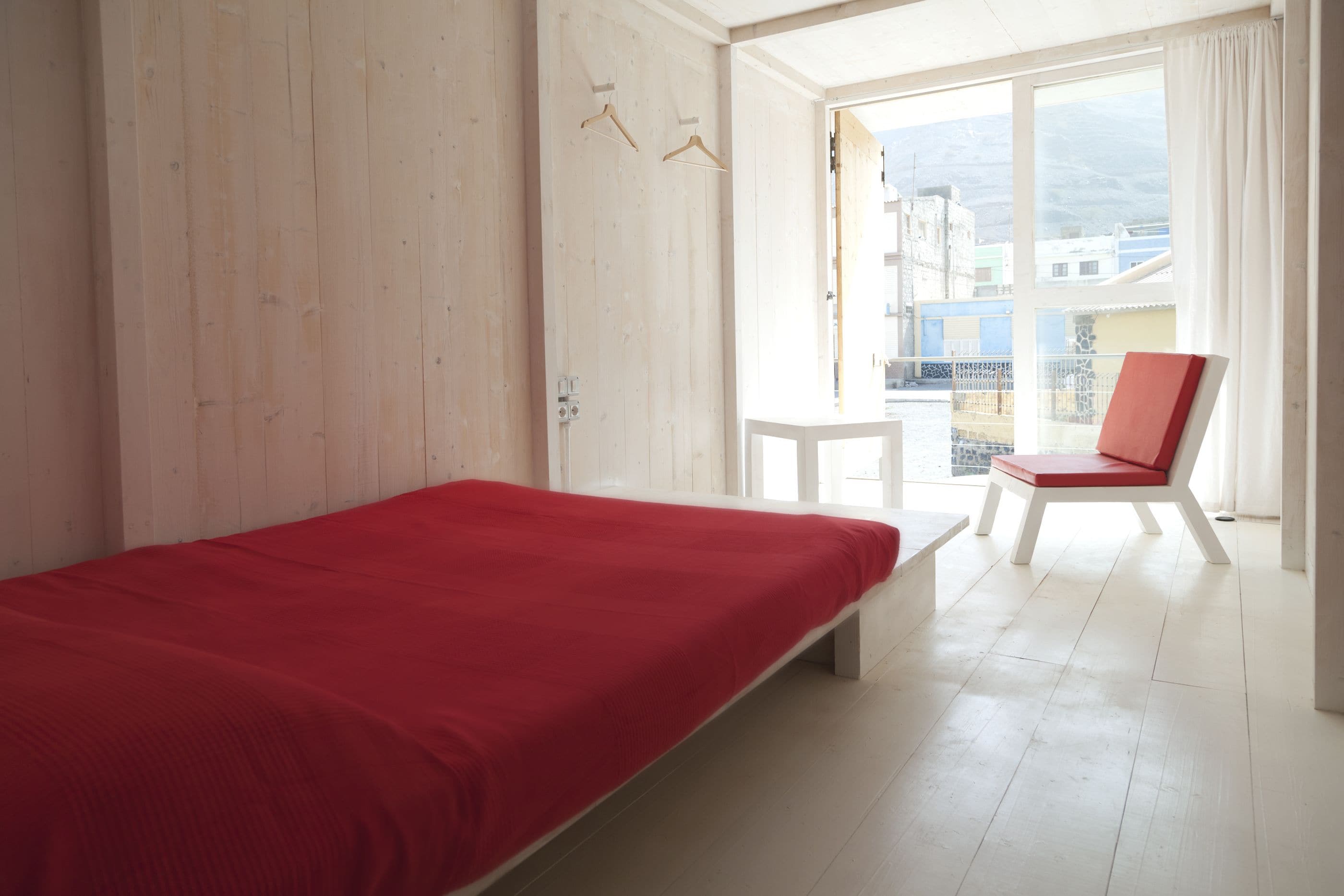 Um quarto com uma cama, uma cadeira e uma mesa.