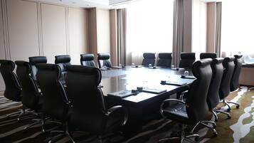 Uma sala de conferências com uma mesa comprida, cadeiras de couro preto e um tapete com padrão de zebra.