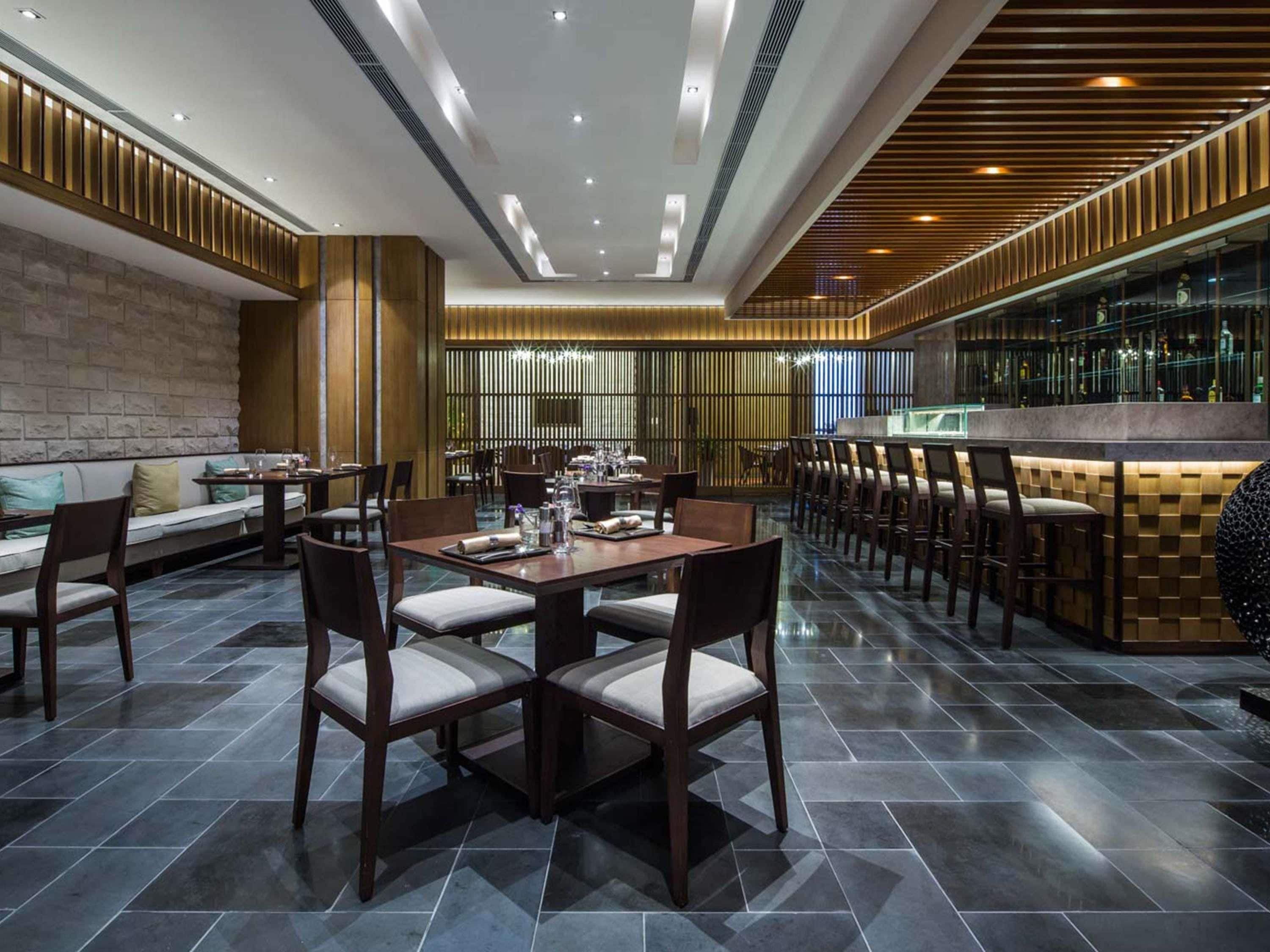 Um restaurante moderno com área de bar, painéis de madeira e parede de pedra.