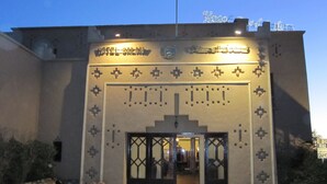 Entrada de hotel com design tradicional, apresentando um arco imponente e um mastro.