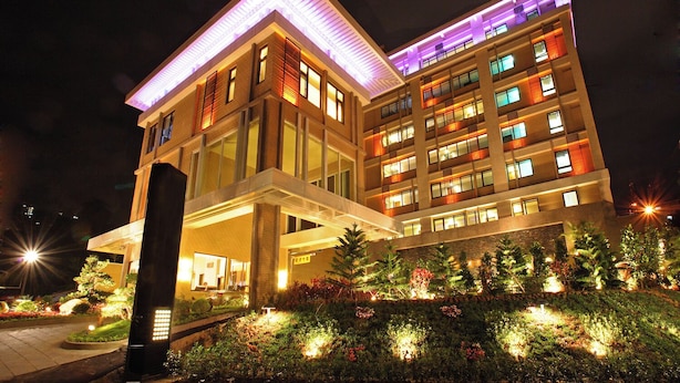 Um hotel com vários andares, varandas iluminadas e uma entrada bem iluminada.