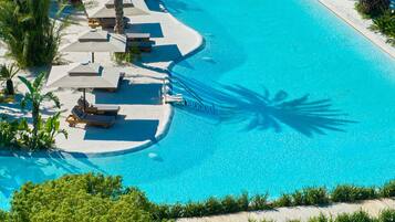 Piscina de resort com espreguiçadeiras e palmeiras.