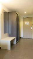 Um corredor com um banco, uma porta com uma placa e piso ladrilhado.