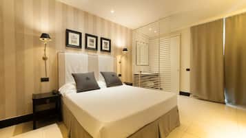 Quarto moderno com uma cama grande, duas luminárias de cabeceira, uma mesinha de cabeceira e um quadro na parede.