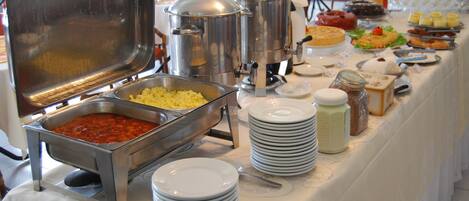 Um buffet com diversos alimentos e utensílios de servir.