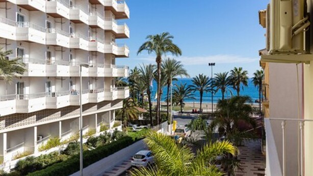 Um hotel com vários andares e varandas com vista para a praia.