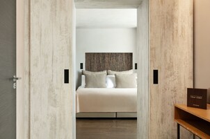 Quarto moderno com cama, cabeceira texturizada e mesa de cabeceira de madeira com um livro.