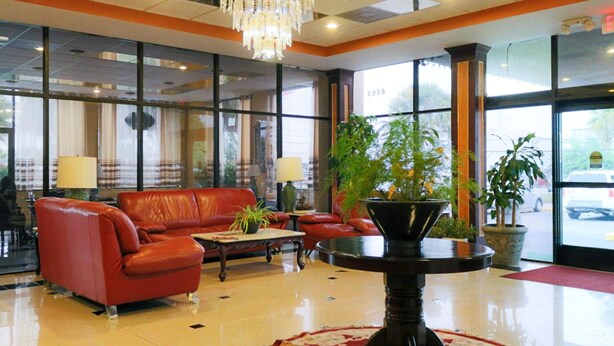 Um lobby com sofás de couro, uma mesa redonda e plantas em vasos.