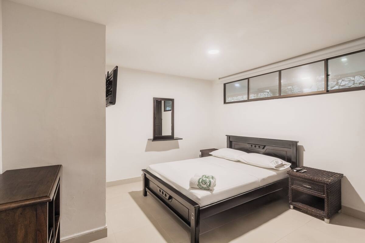 Quarto com uma cama, mesa de cabeceira e um pequeno armário.