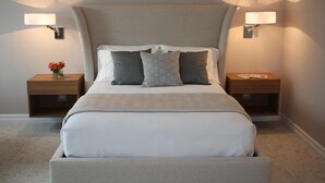 Quarto moderno com uma cama grande, duas mesas de cabeceira e luminárias fixadas na parede.