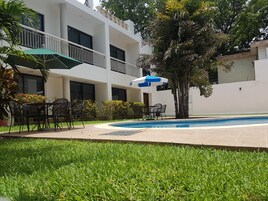Um edifício moderno com piscina, área de estar ao ar livre e vegetação.