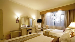 Quarto de hotel com duas camas, uma escrivaninha, uma cadeira, uma televisão e uma janela com cortinas.
