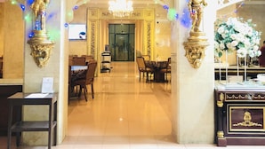 Um hall de entrada com um candelabro, colunas elaboradas e um balcão de recepção.