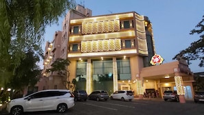 Um hotel com vários andares, com padrões iluminados na fachada, um estacionamento com vários carros e uma placa indicando o nome do hotel.
