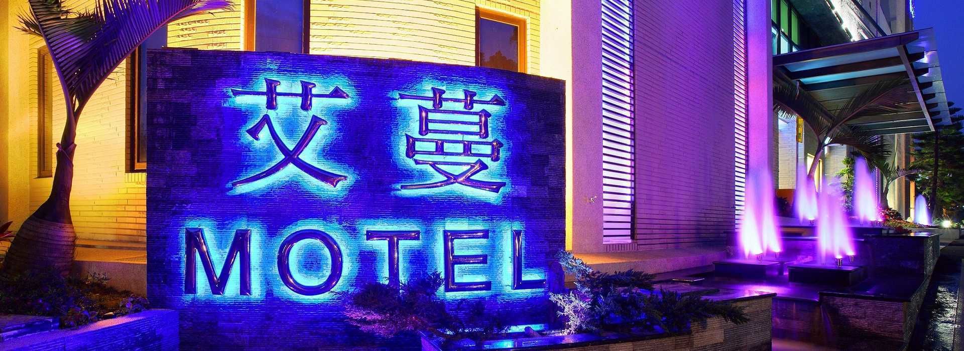 Um letreiro de motel com letras de neon iluminadas que formam a palavra 'MOTEL' e caracteres chineses acima.