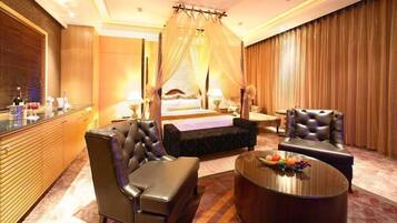 Um quarto de hotel luxuoso com cama de dossel, assentos de couro, uma mesa de centro redonda e um minibar.