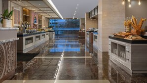 Um lobby de hotel moderno com um balcão comprido, vitrines de vidro e vista para o exterior.