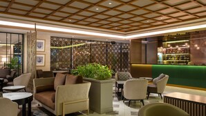 Uma área de estar moderna com sofás, mesas e um bar.