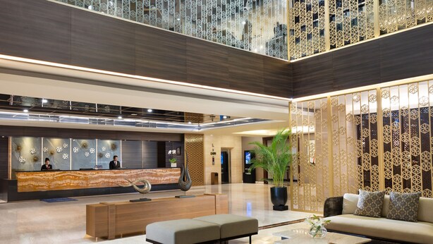 Um lobby moderno com balcão de recepção, área de estar e painéis decorativos.