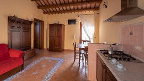 Uma cozinha compacta com fogão a gás, armários de madeira e um espaço de jantar com cadeiras e mesa.
