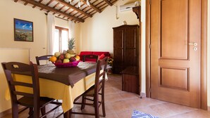Uma área de refeições com uma mesa de madeira, cadeiras e uma cesta de frutas.