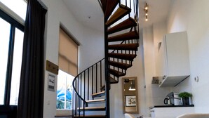 Um interior moderno com escada em espiral, um sofá, uma mesa de jantar e uma área de cozinha.