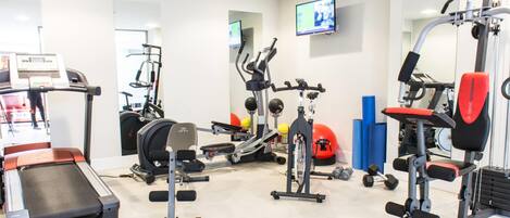 Academia com esteiras, aparelhos de musculação e bolas de exercício.