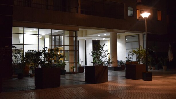 Um edifício com grandes janelas de vidro, plantas em vasos e um poste de luz.