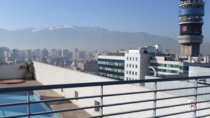 Piscina no terraço com vista para a paisagem urbana e montanhas ao longe.