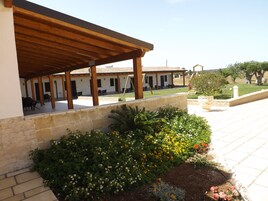 Área externa coberta com paredes de pedra e um jardim com diversas flores.