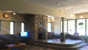 Uma sala de estar aconchegante com lareira de pedra, assentos confortáveis e uma televisão.