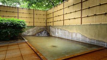 Uma onsen japonesa tradicional com uma nascente quente de pedra, soalho em azulejo e paredes de bambu.