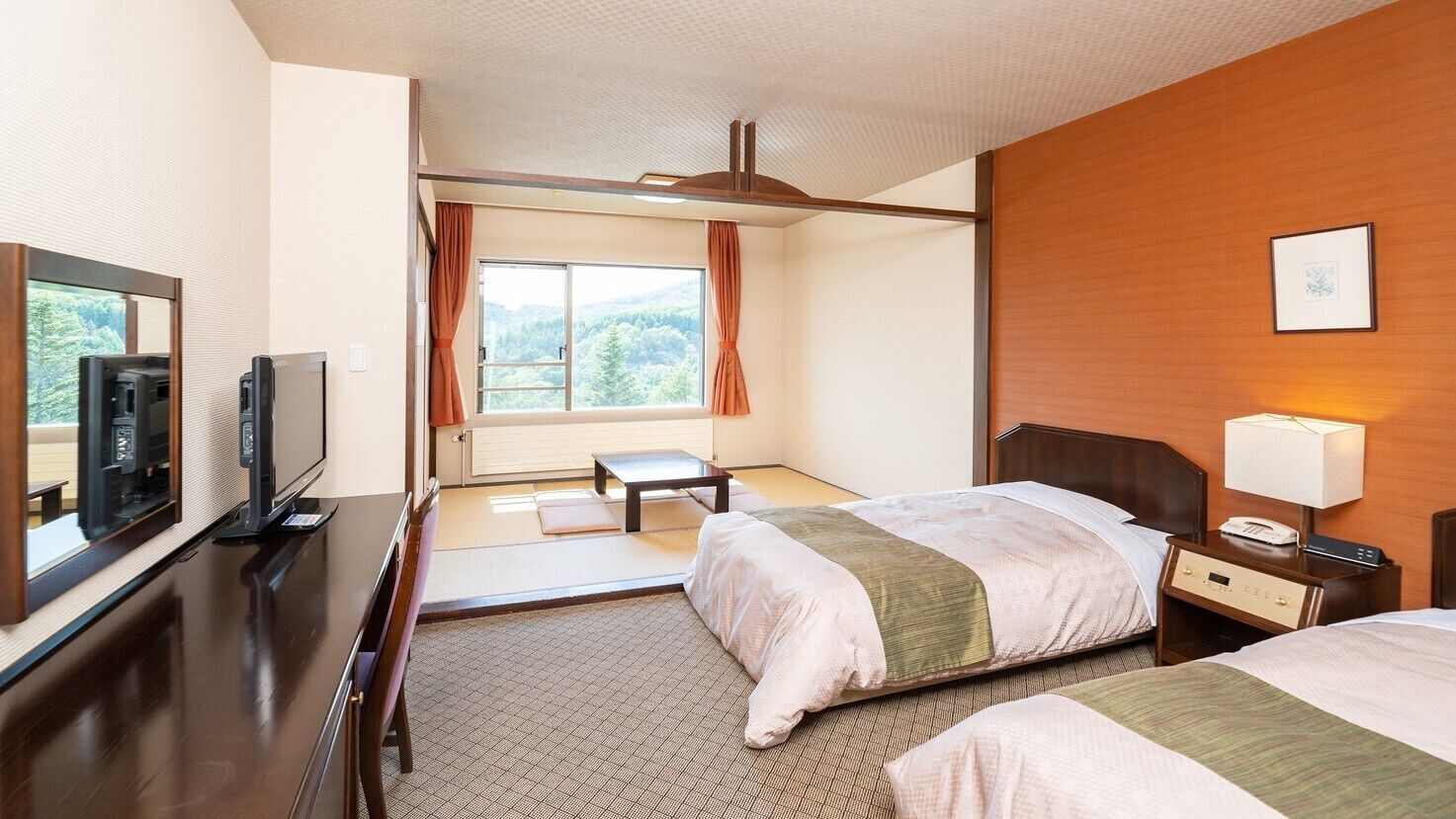 Quarto de hotel com duas camas, televisão, escrivaninha e janela com cortinas.