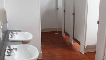 Sanitário com duas pias, espelho e chão revestido de azulejos.