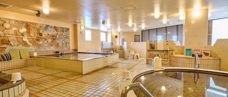 Um spa com uma grande banheira de hidromassagem, área de massagem e piso ladrilhado.