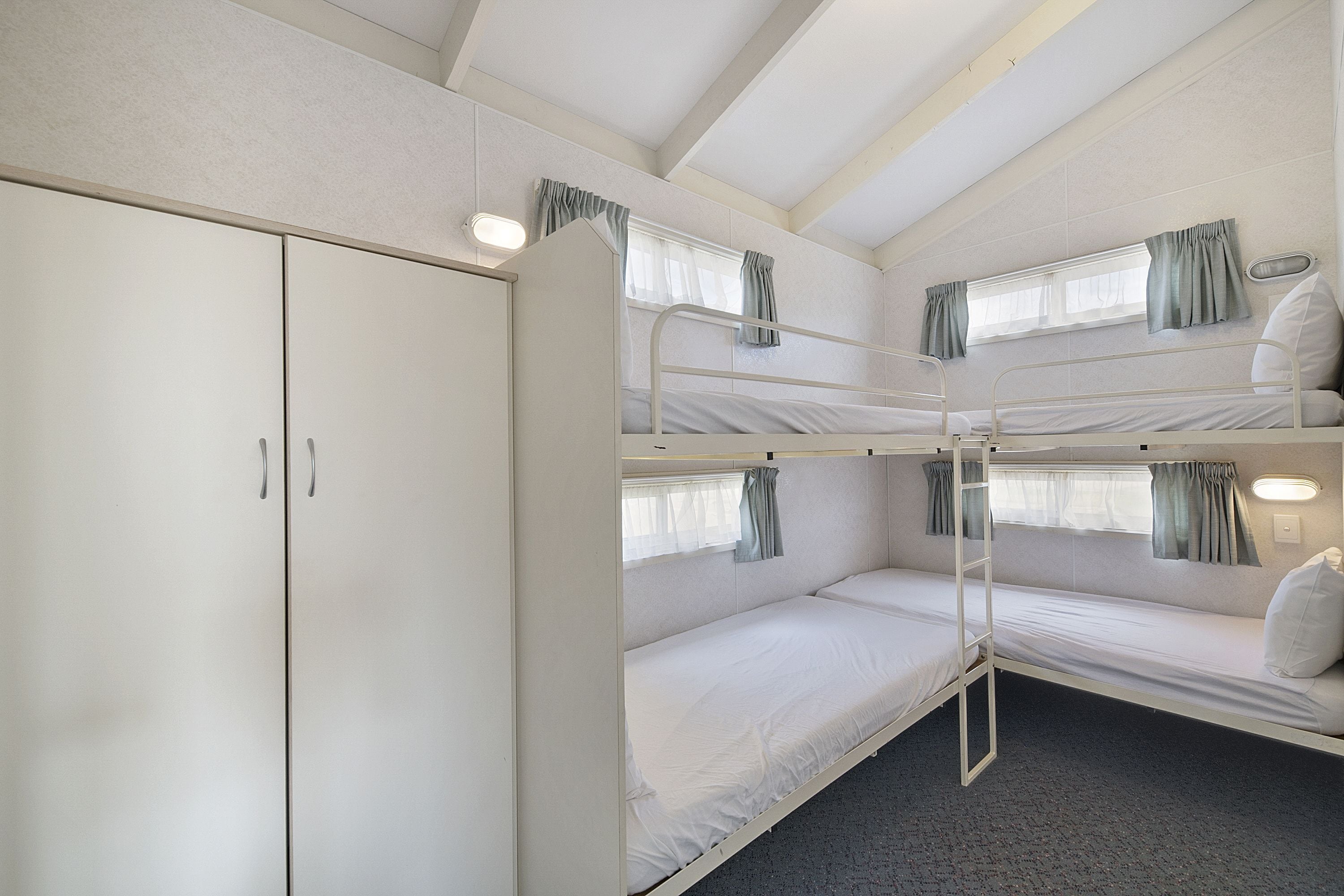 Quarto com beliche, guarda-roupa e escada.