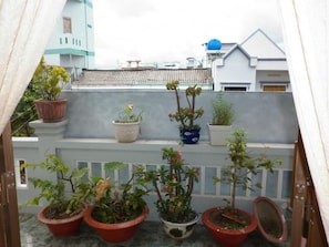 Um jardim no terraço com diversos vasos de plantas e um pequeno espaço de estar.