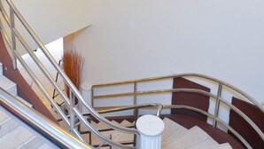 Um hall de hotel com um lustre imponente, uma escadaria e um balcão de recepção.
