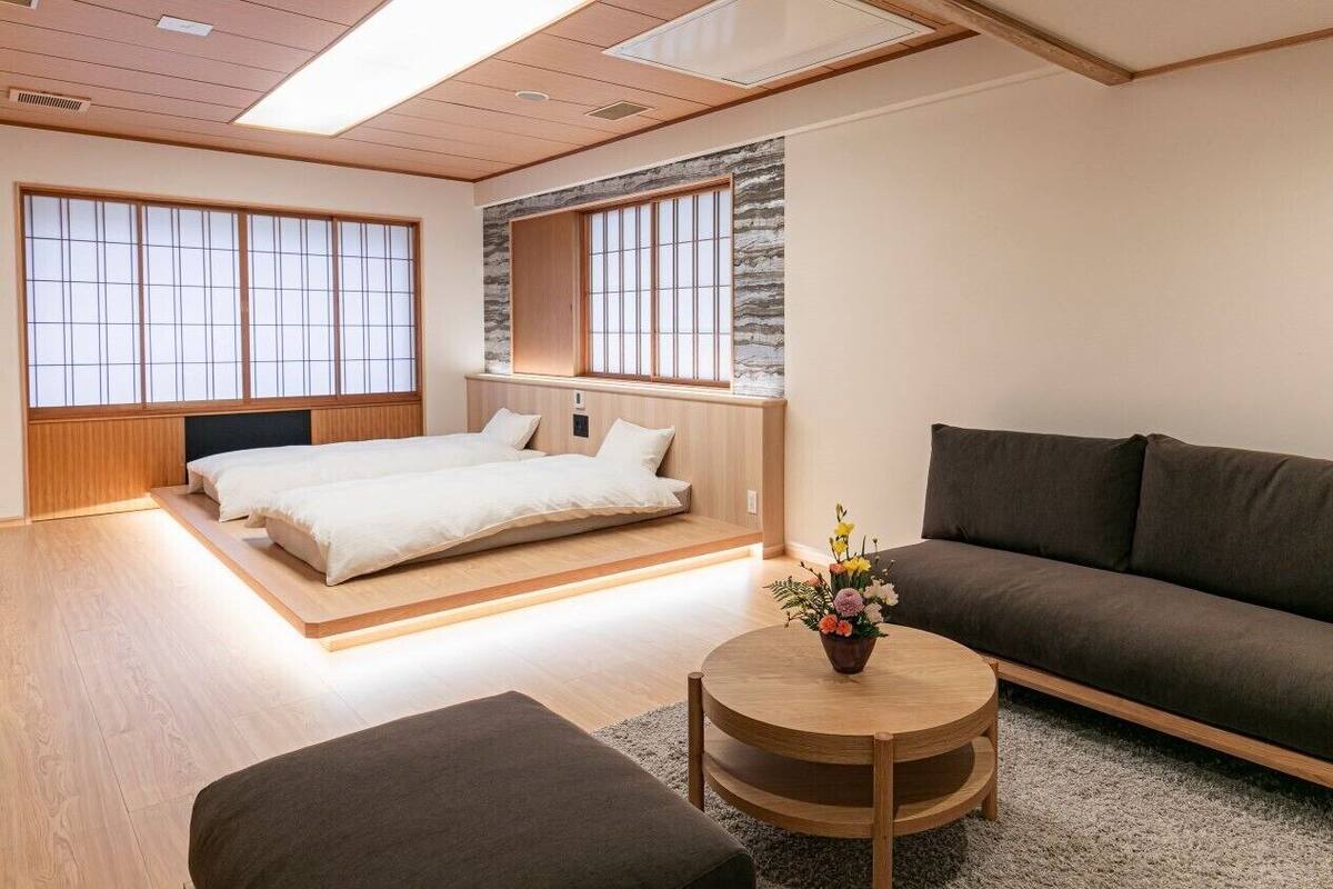 Quarto moderno com cama, sofá e mesa redonda com flores.