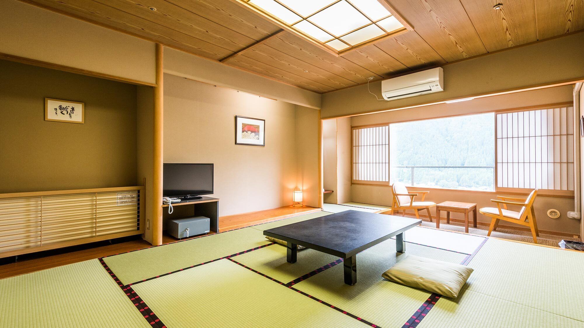 Quarto japonês tradicional com tatames, televisão, aquecedor, futon e vista para o exterior.
