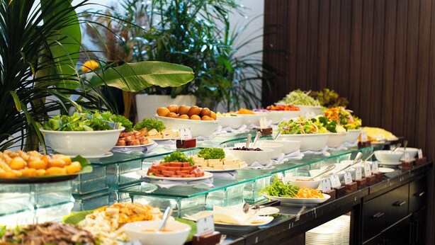 Buffet com diversos alimentos e uma vitrine de vidro.
